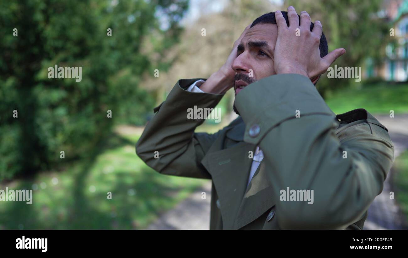 Preoccupied man standing outside at park having a regretful memory ...