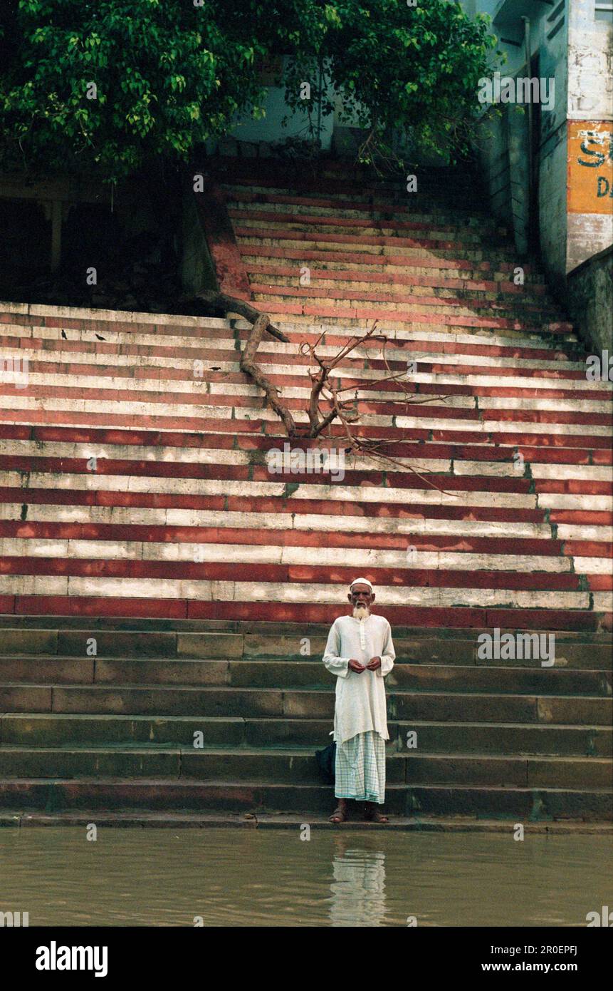Praying pilgrim standing on stairs at the river Ganges, Ghat, Varanasi ...