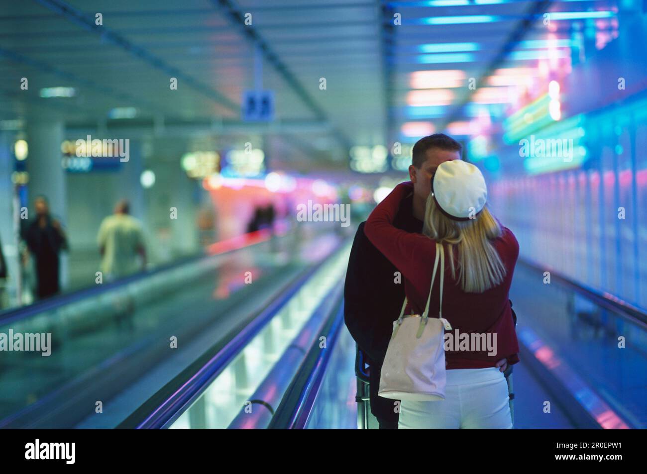 Couple kissing on a moving walkway, Munich Airport, Munich, Germany ...