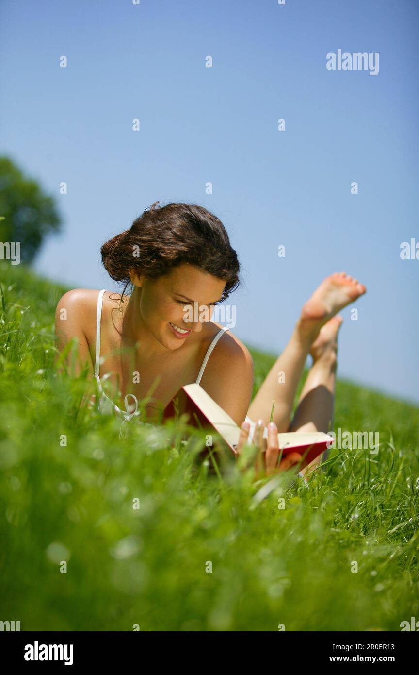 Young Woman reading book on lawn, Young Woman lying in meadow and ...