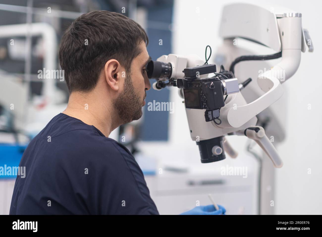 Bearded doctor looking in modern dental microscope to check cavity of ...