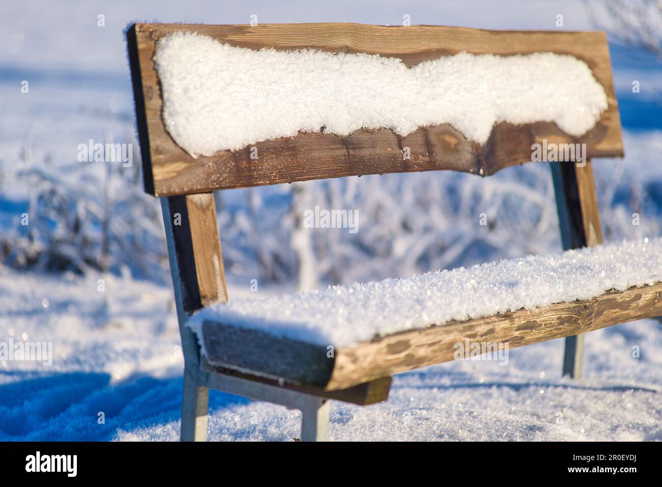 A wooden bench is seen in a winter wonderland, covered in a layer of ...