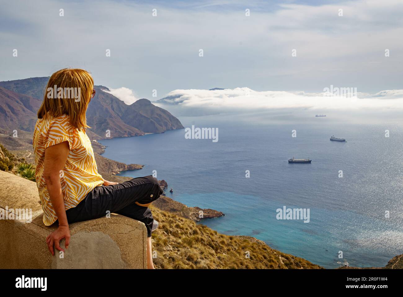 Woman contemplating the Mediterranean sea from the top of the hill ...