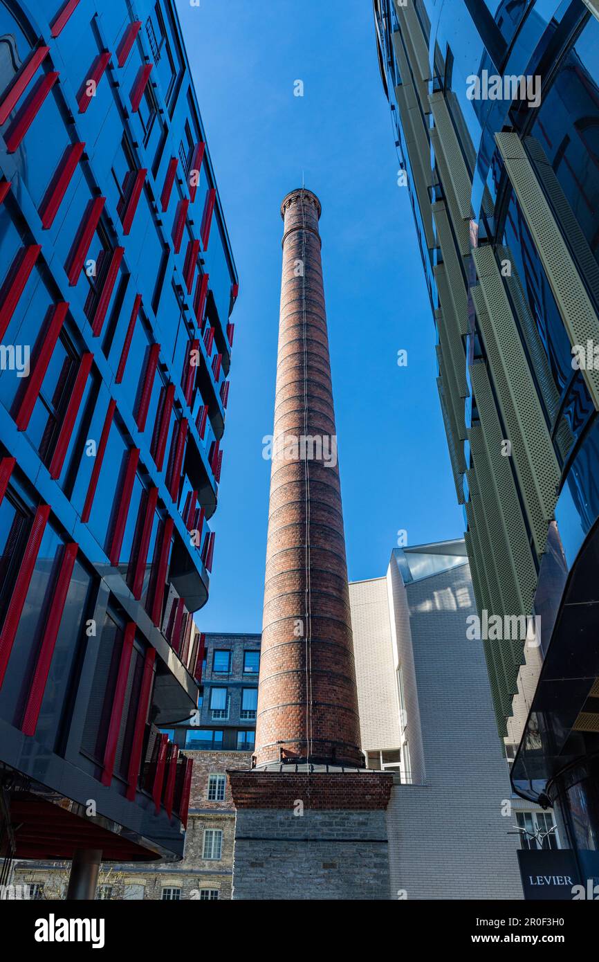Old industrial chimney or smokestack between modern buildings in ...