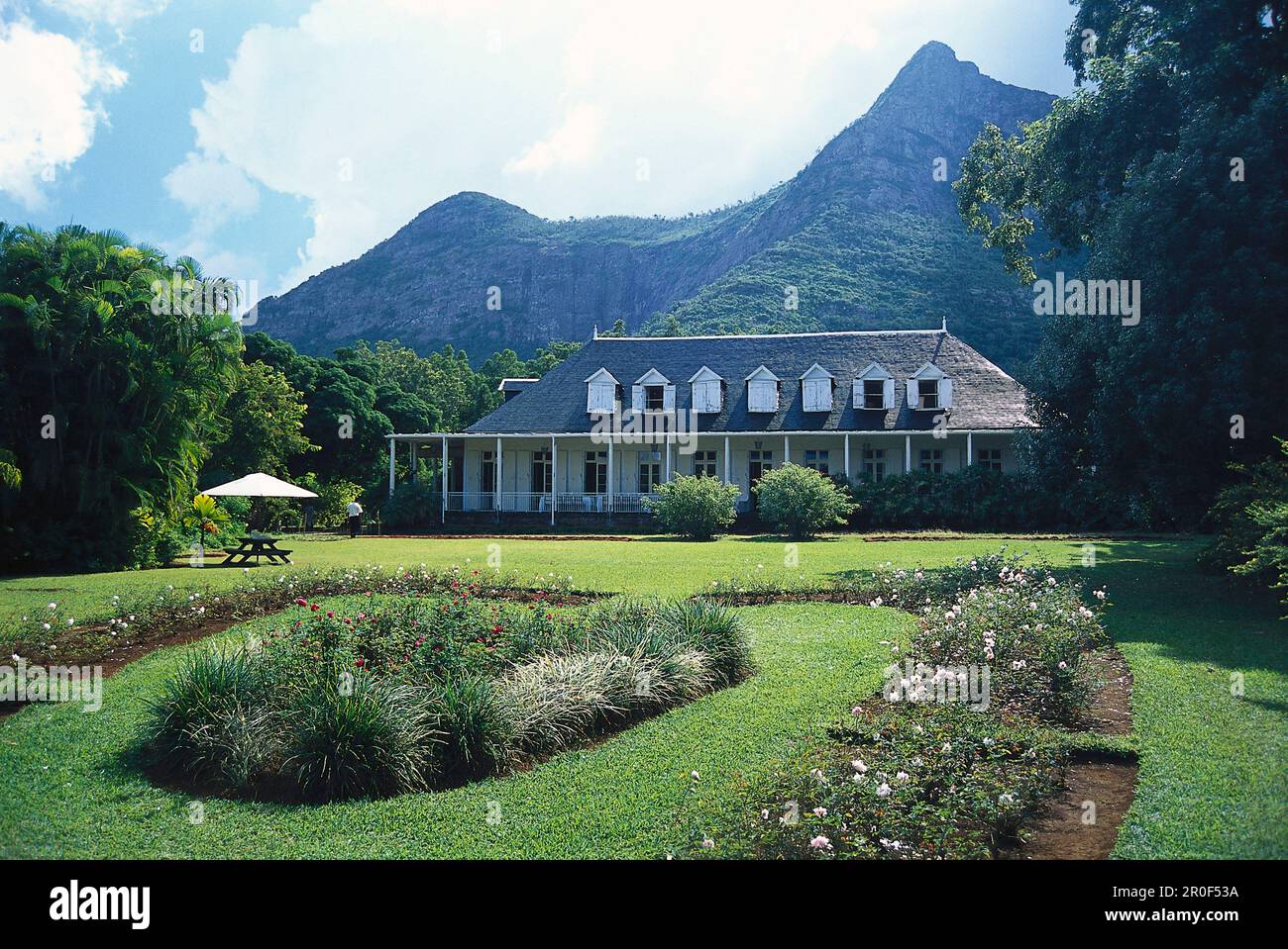Historical colonial style house and garden in front of a mountain ...