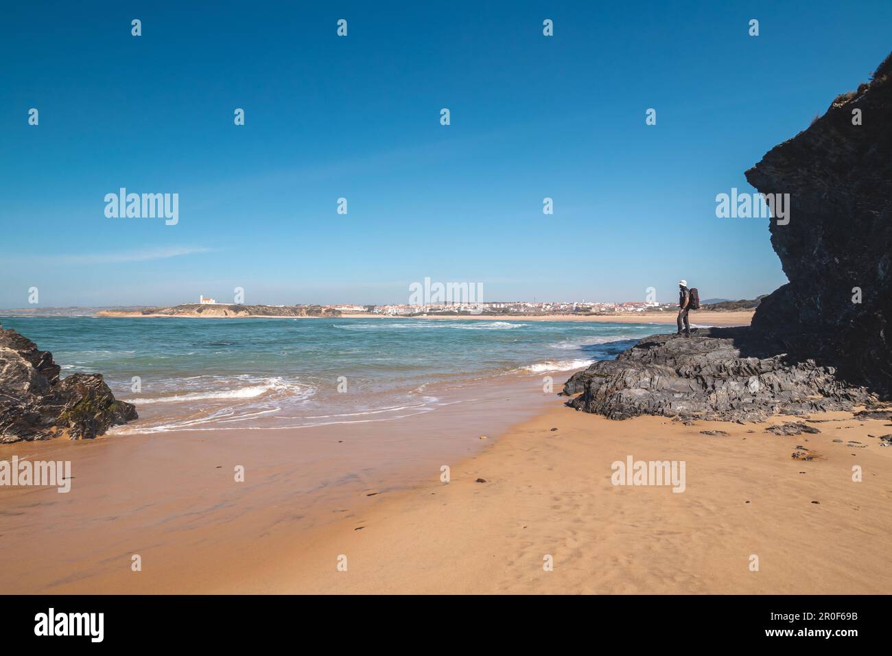Elderly man with a backpack standing on a rock enjoying the view of ...