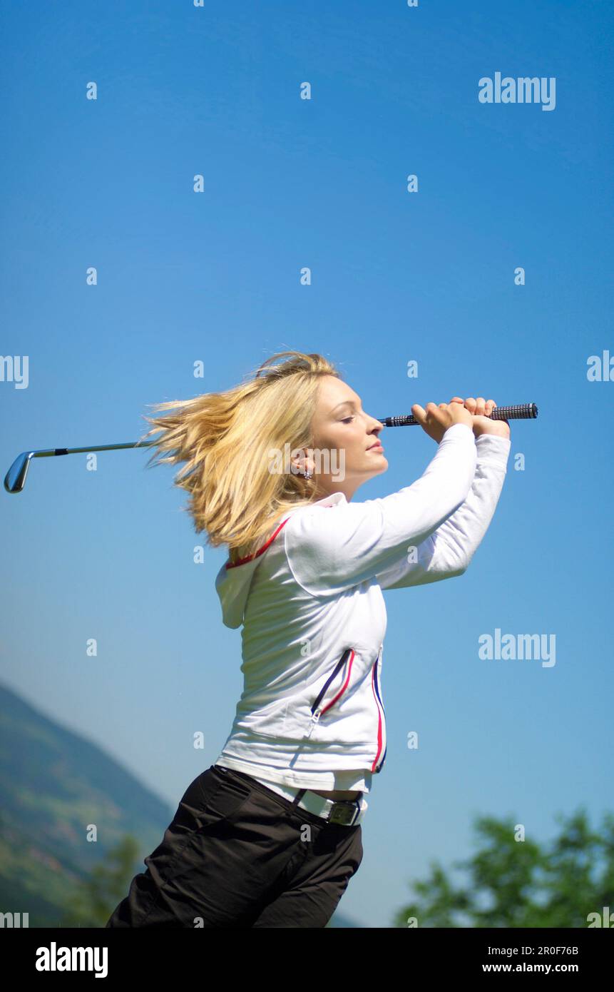 Young woman with blond hair hitting golf ball Stock Photo - Alamy