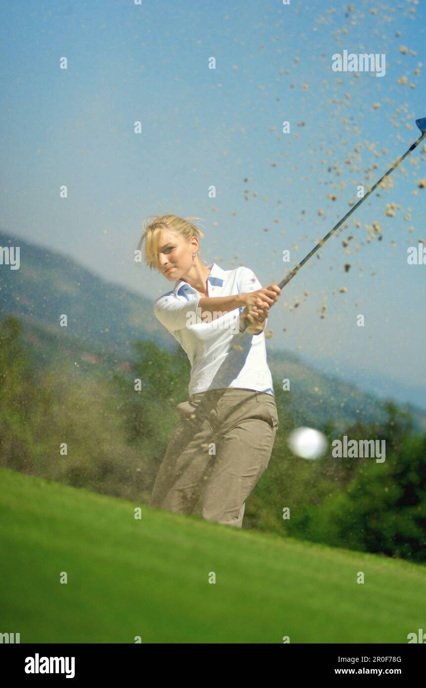 Young woman with blond hair hitting golf ball on the golf course Stock ...