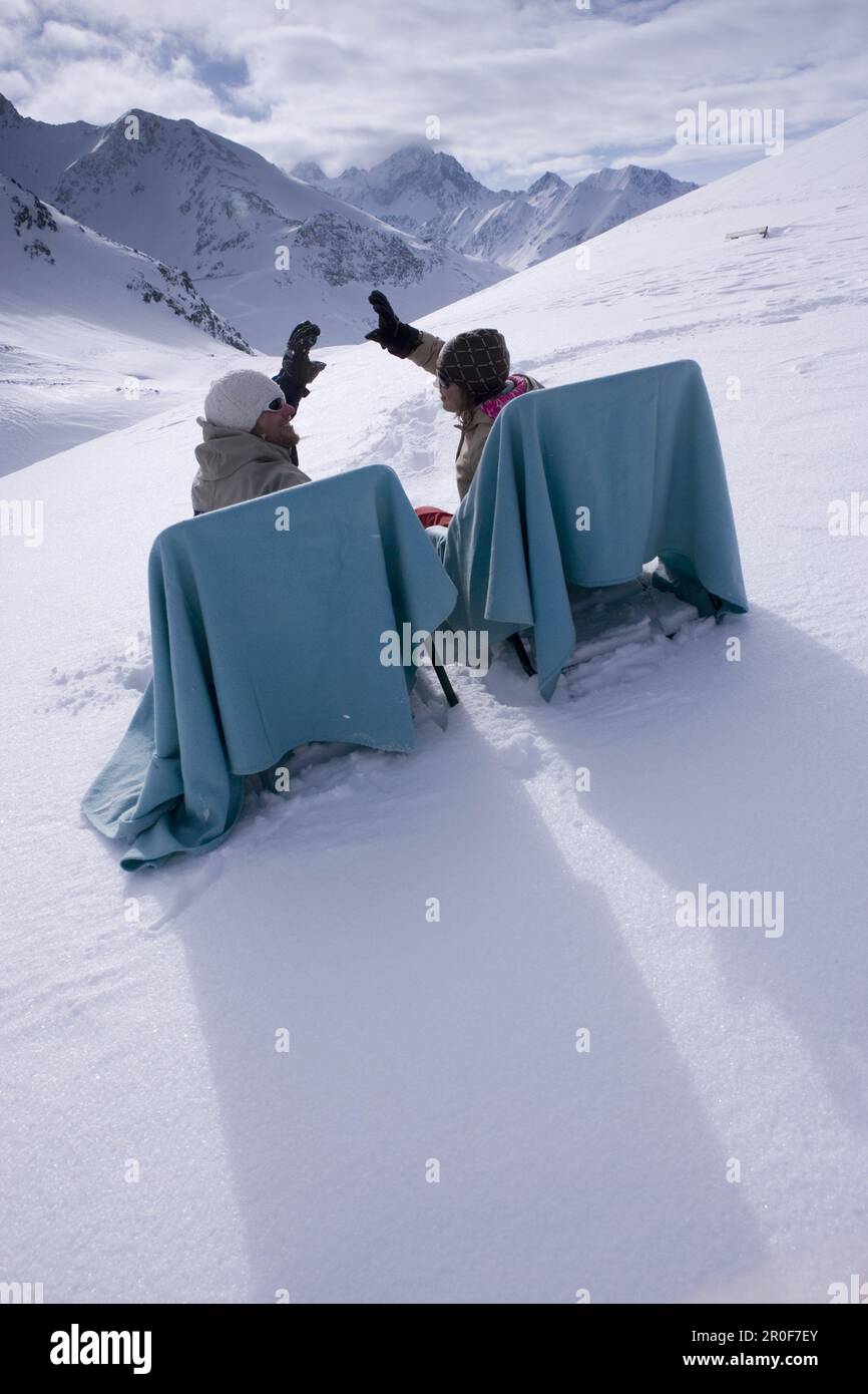 Two young people relaxing on lounge chairs on snow, Kuehtai, Tyrol ...