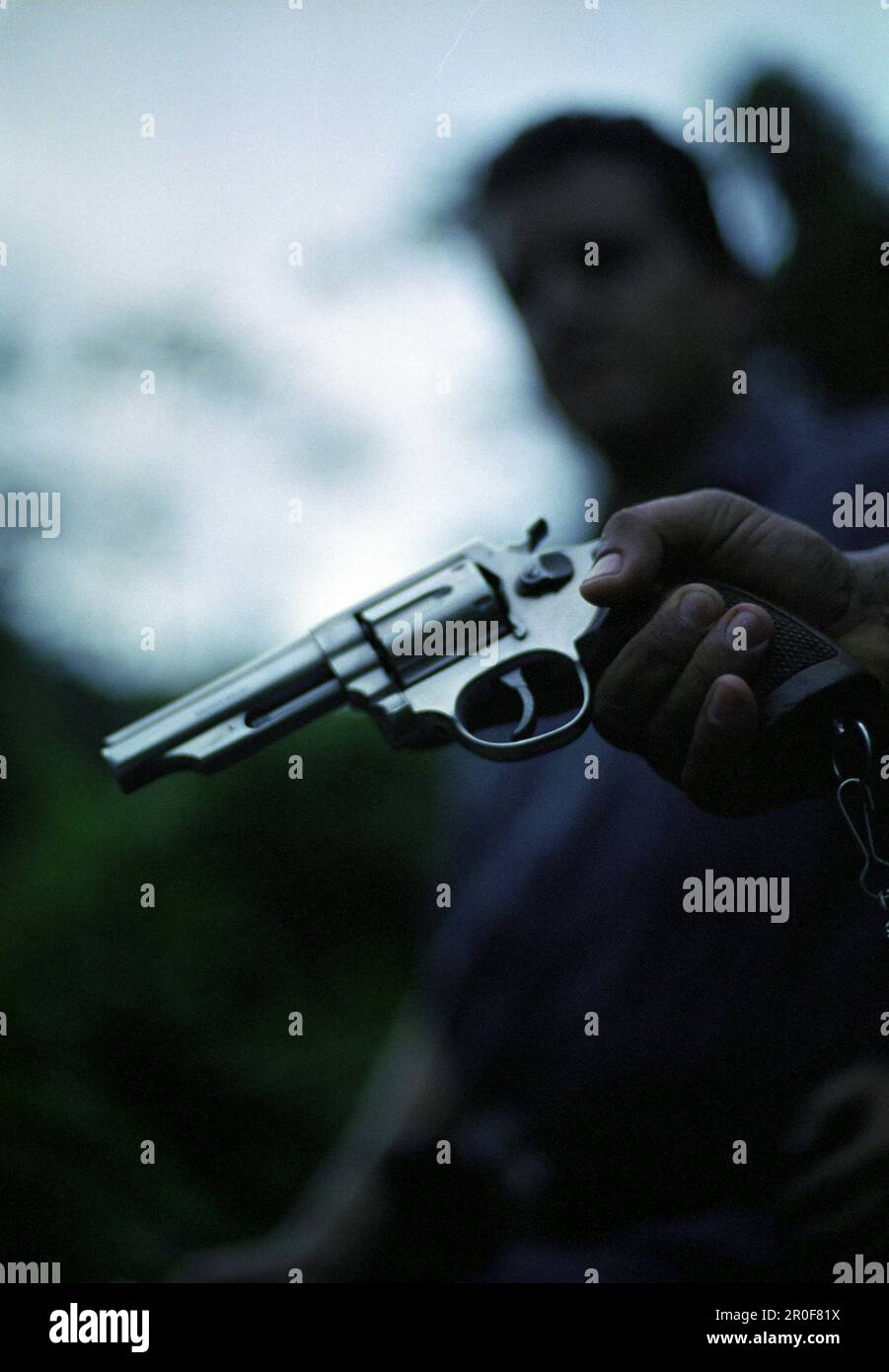 Hand holding a gun, group of people in background Stock Photo - Alamy
