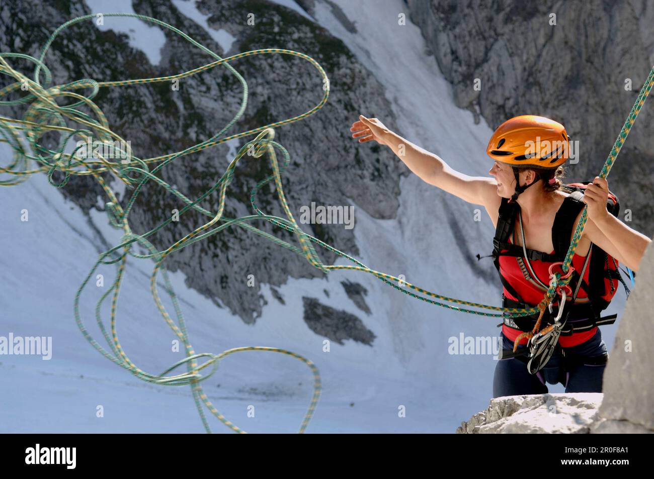 Female climber throwing rope during abseiling from Wilder Kaiser ...
