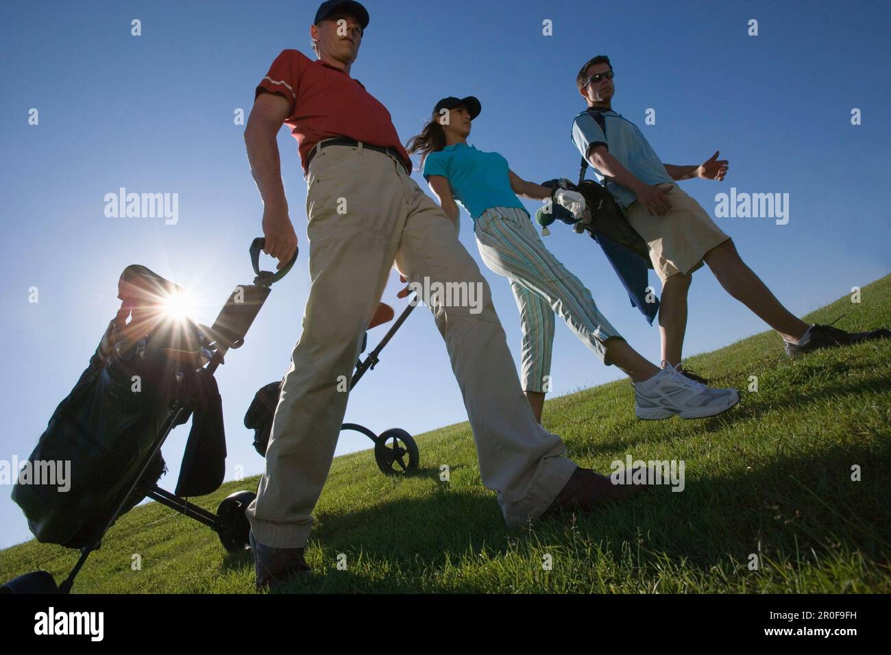 Group of people walking on golf course pulling golf bag on wheels ...