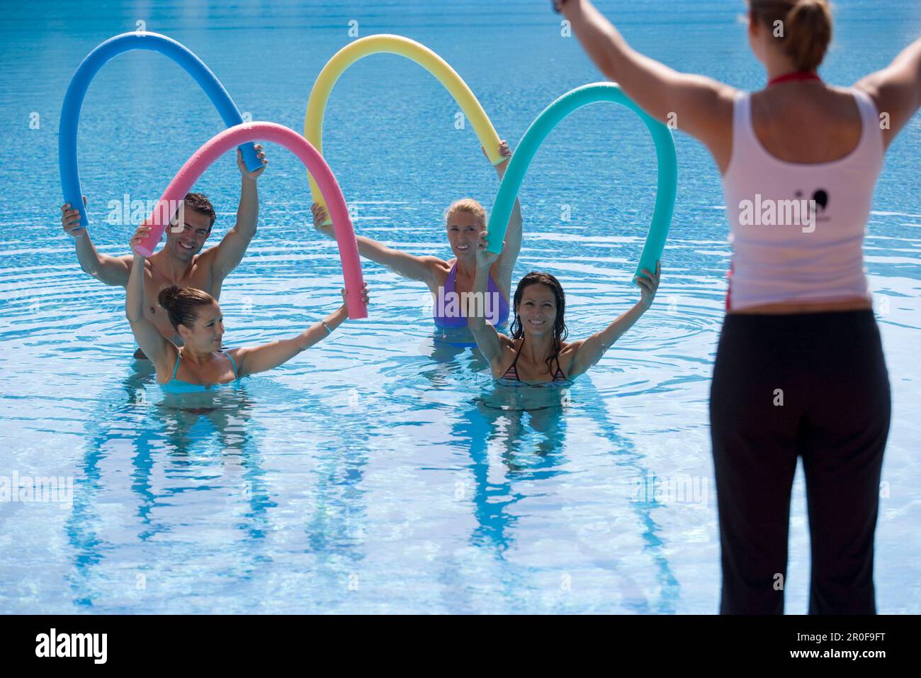 Trainer showing young people stretching exercises in pool, Apulia ...