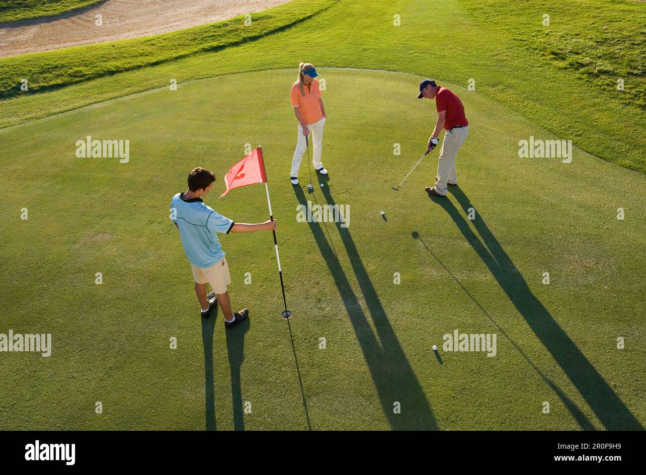Golfers on golf course, long shadows Stock Photo - Alamy
