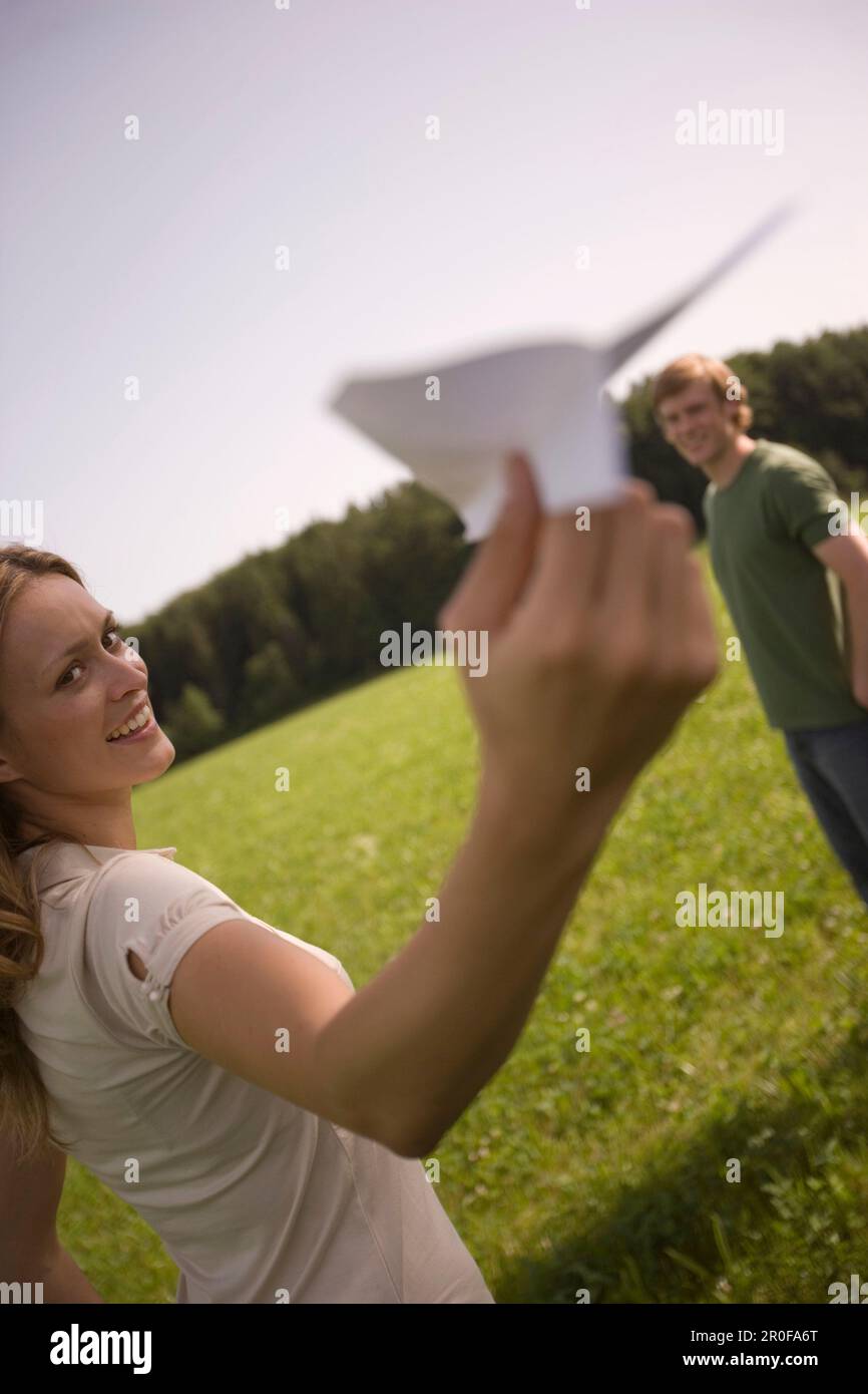Young woman throwing paper airplane on meadow Stock Photo - Alamy