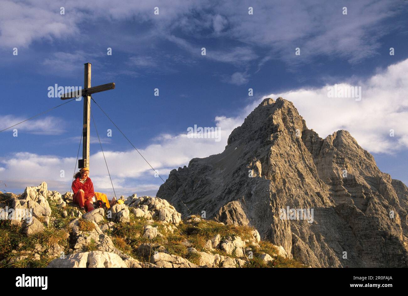 Mountaineer and summit cross with a view of the Watzmann, Berchtesgaden ...