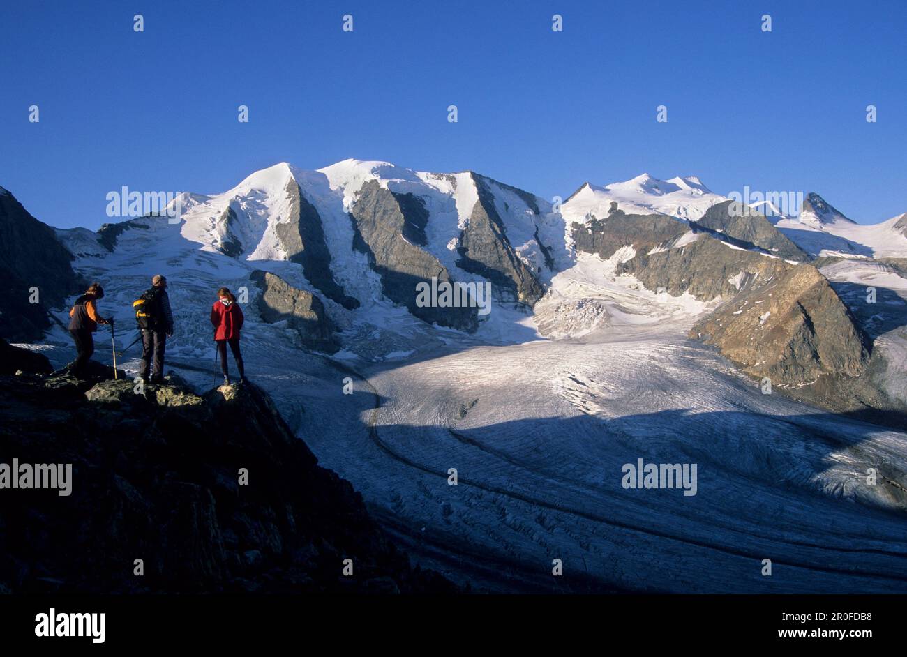 Three alpinists enjoying view to mount Piz Palue and glacier of Pers ...