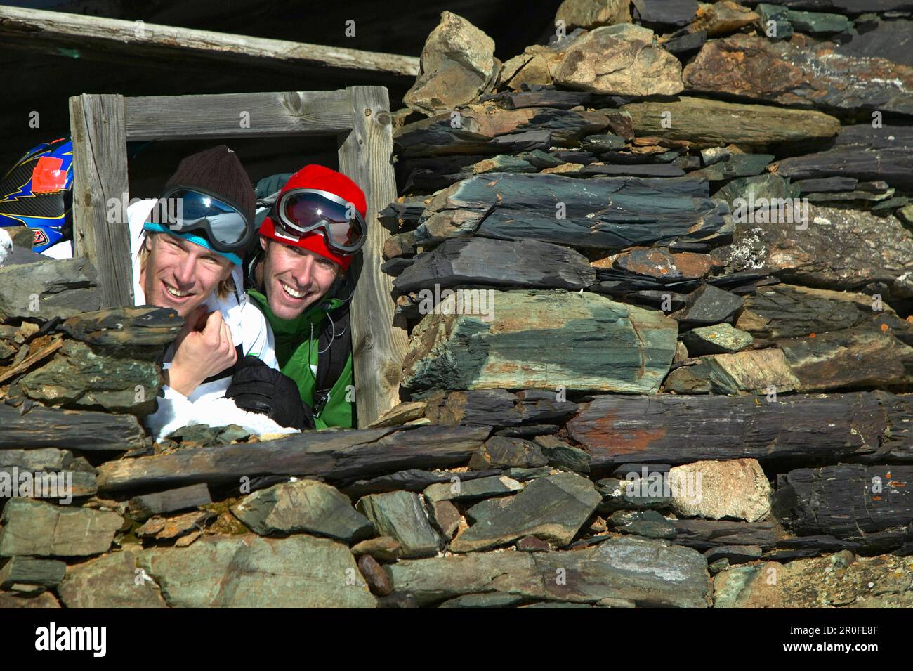 Two snowboarder looking through window of derelict cabin, Falkertsee ...