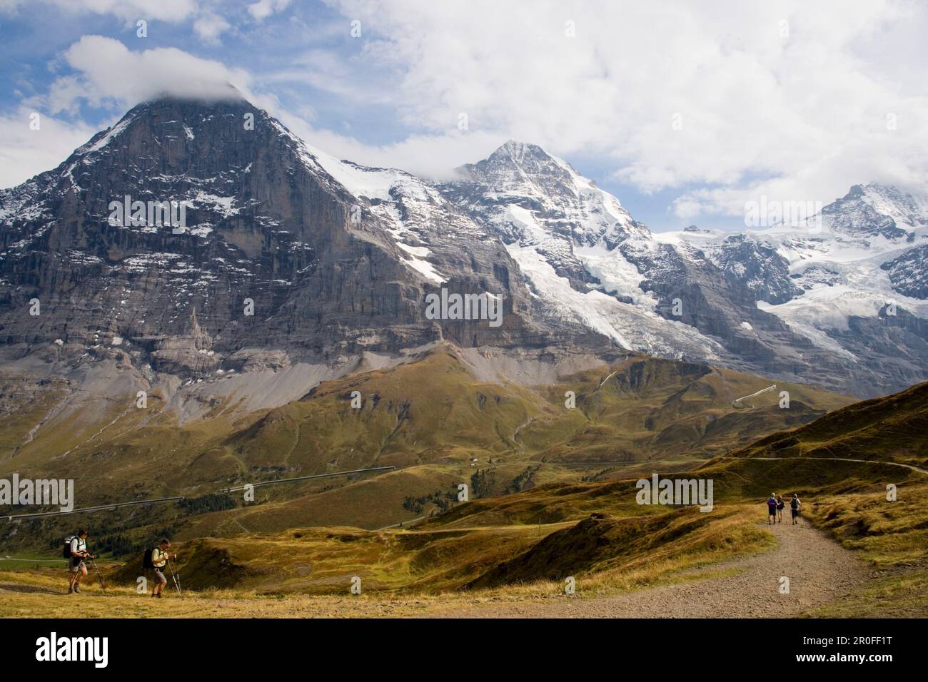 People hiking along Maennlichen panorama hiking path, Eiger 3970 m, Moench 4107 m and Jungfrau ...
