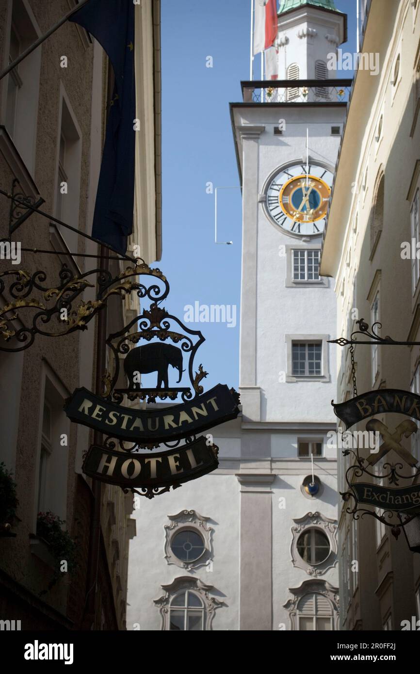 Wrought-iron shop sign at a house wall, city hall tower in background ...