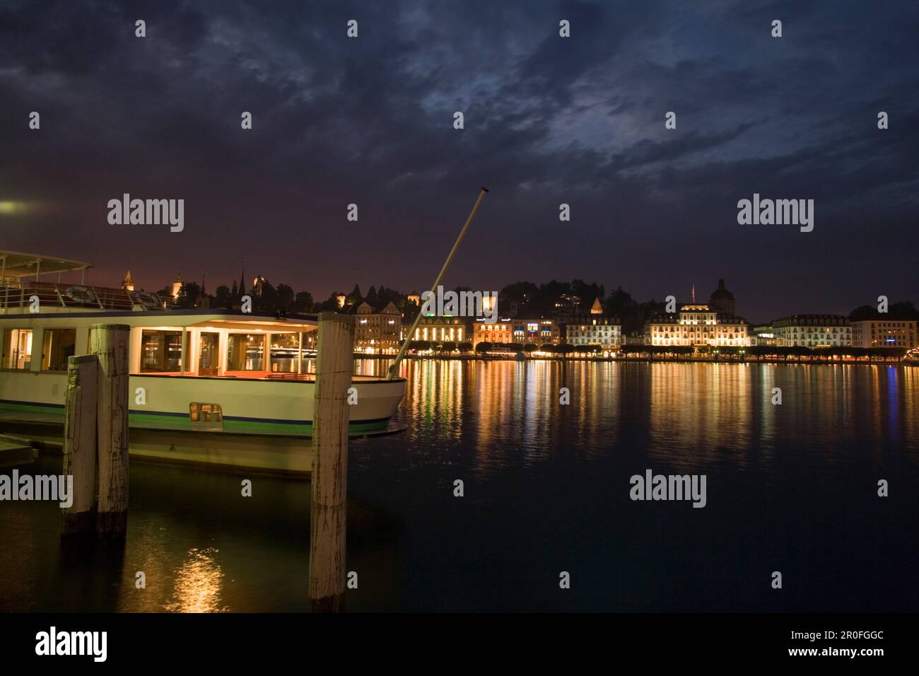 View from jetty over Lake Lucerne to illuminated Hotel Schweizerhof ...