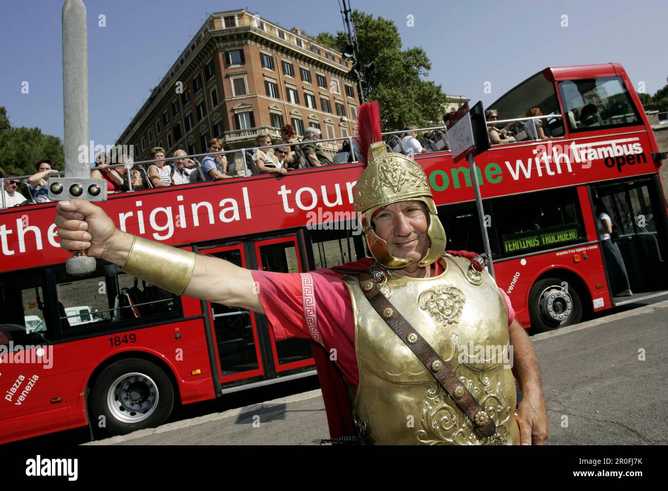 Man in Roman costume posing for tourist in front of sightseeing bus at ...