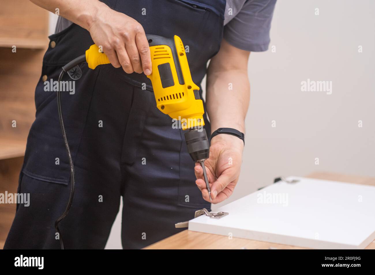 Furniture installing handyman in coveralls using drilling machine for ...