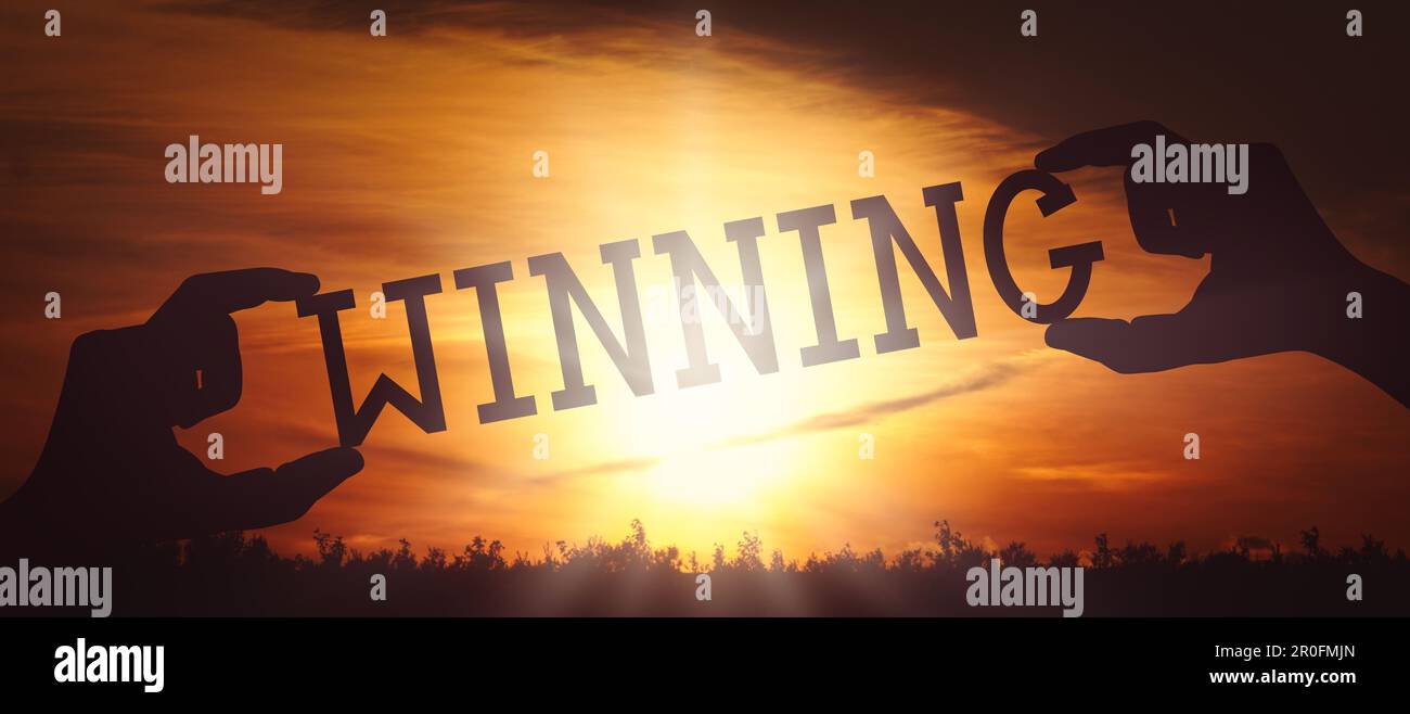 Winning - human hands holding black silhouette word Stock Photo - Alamy