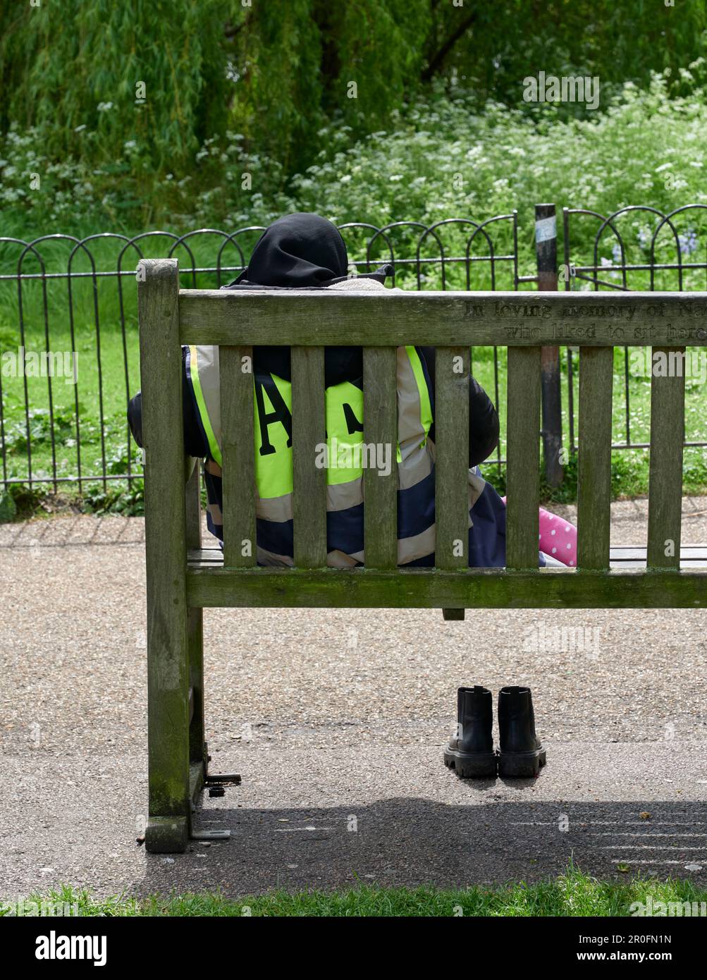 Female security guard resting with feet up on wooden bench in St James ...