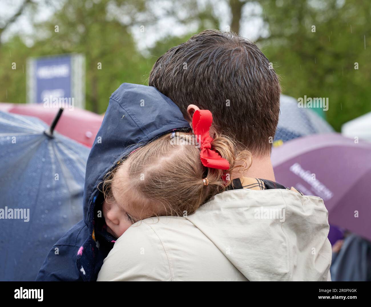 Young girl resting on (presumed) father's shoulders during rainfall in ...