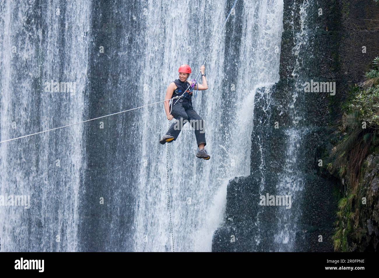 Woman hanging on a rope in front of a waterfall, Grabouw Forest Park ...