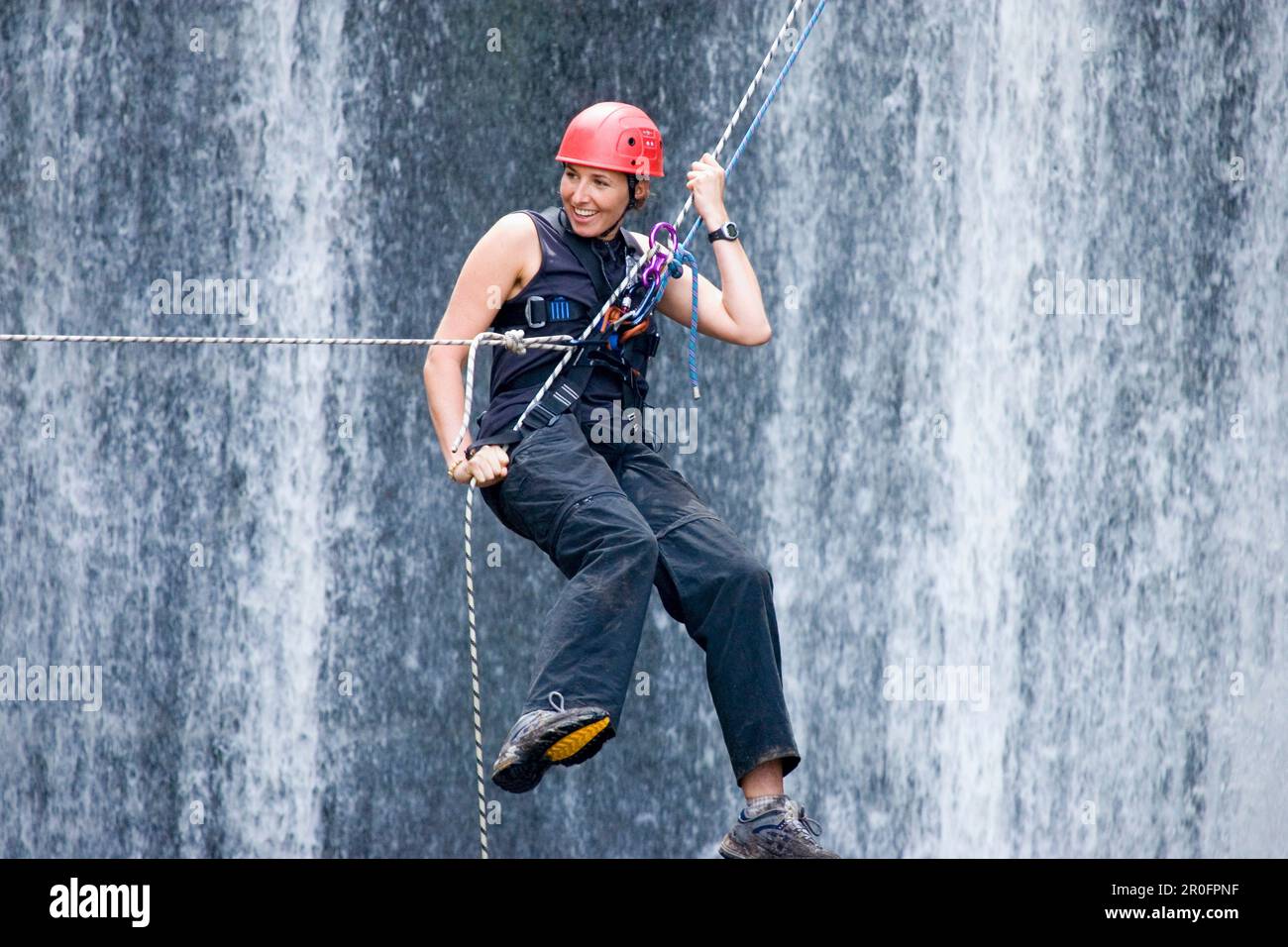 Woman hanging on a rope in front of a waterfall, Grabouw Forest Park ...