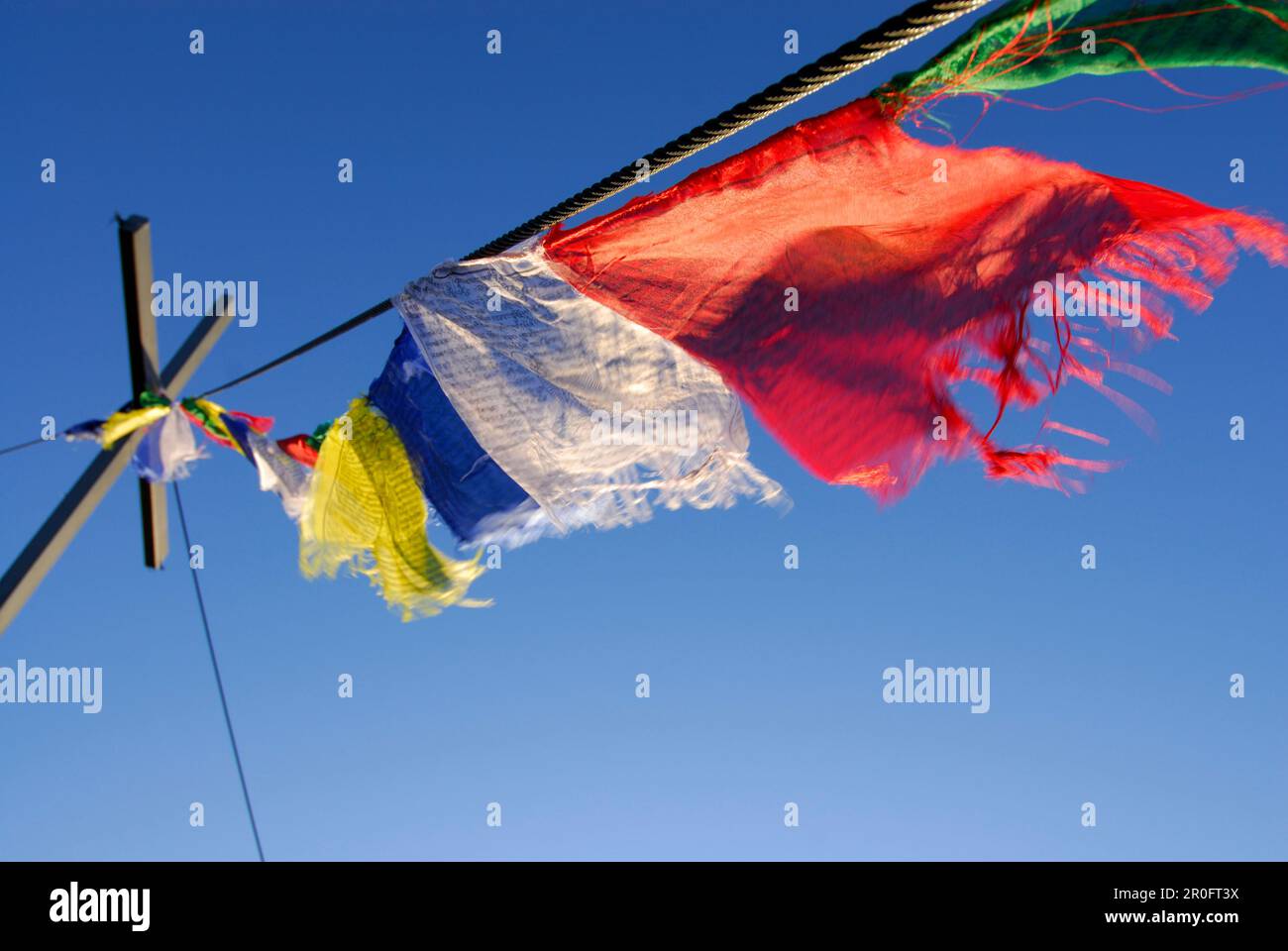 Prayer flags at summit cross on mountain Ellmauer Halt, Kaiser range ...
