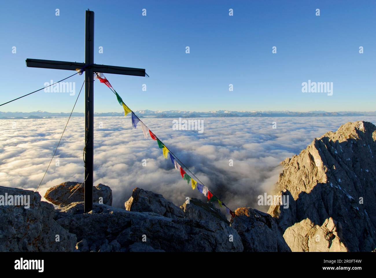 Summit cross with prayer flags on mountain Ellmauer Halt, Kaiser range ...