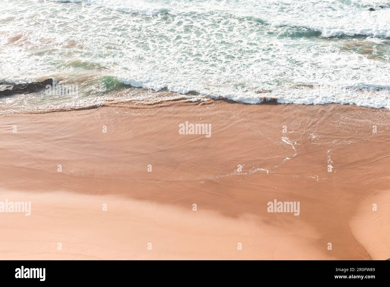 Gentle flow of blue-green waves on a yellow sandy beach in the Odemira ...