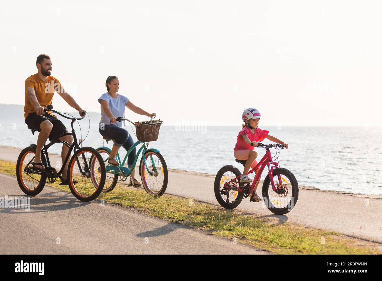 Mother, father and girl child having fun on vacation cycling near the ...