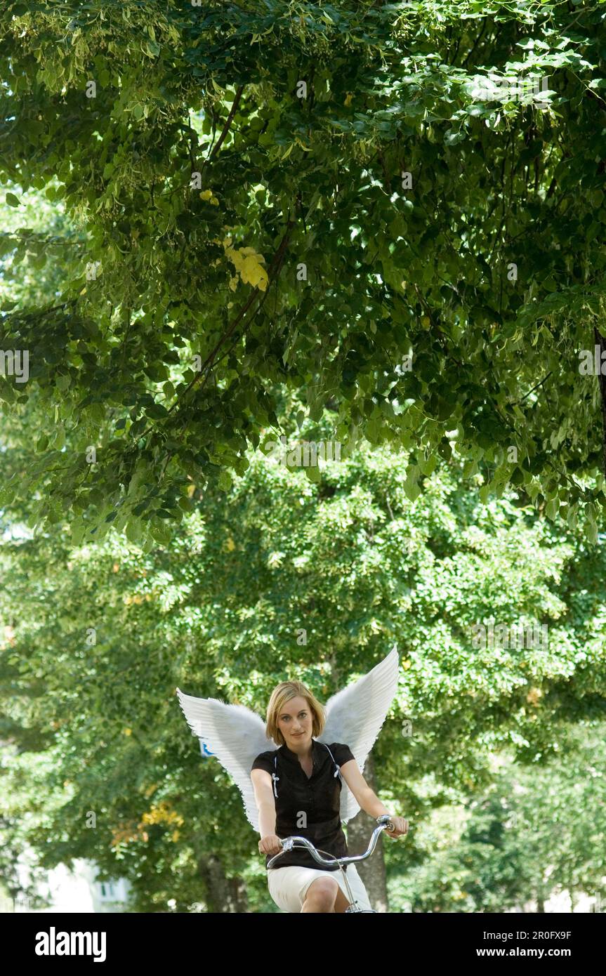 Angel, young woman with wings riding a bike, Munich, Bavaria, Germany ...