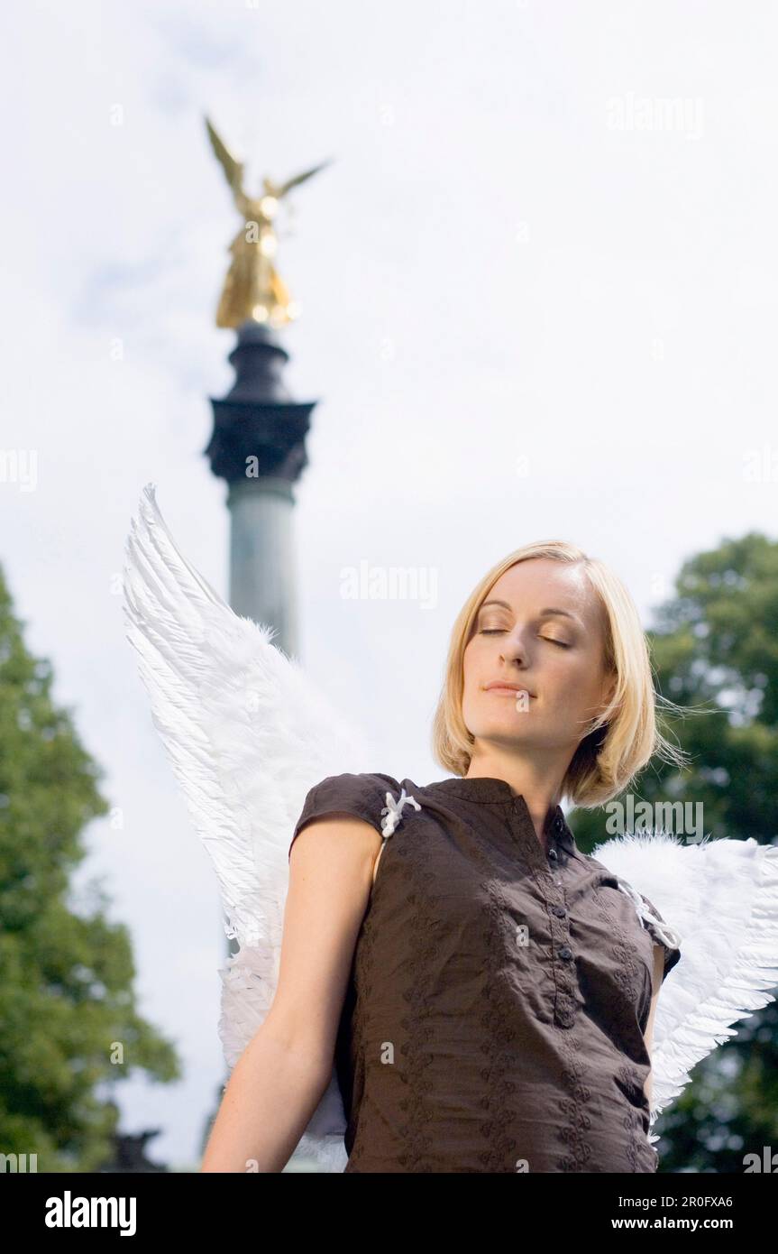 Mid adult woman wearing angel wings near Friedensengel, Munich, Bavaria ...
