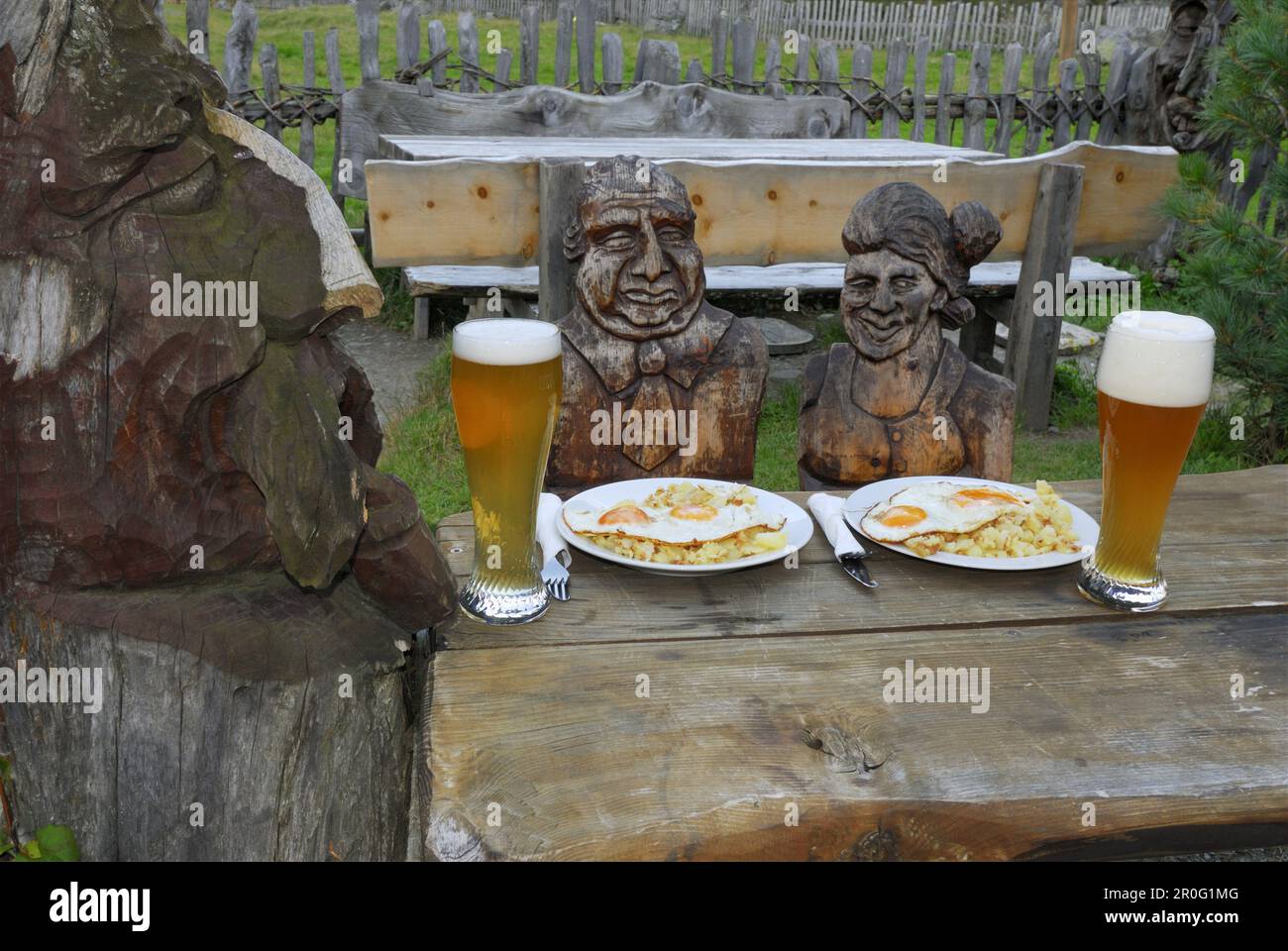 Carved couple at a table with food and wheat beer, alpine lodge Sulzenau, Stubaier Alps, Stubai ...