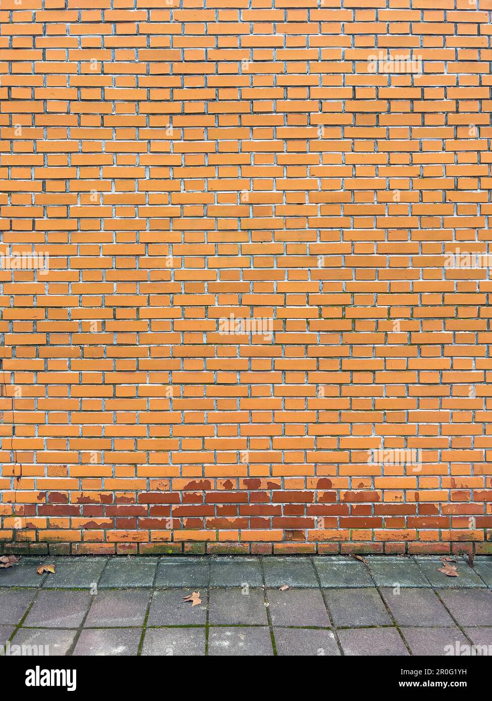 An urban brick wall on a city street, with a textured and weathered ...