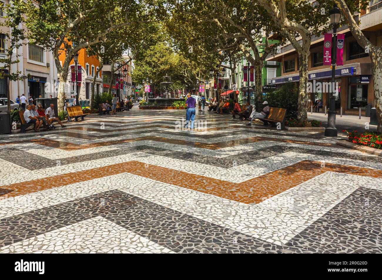 A lively city plaza surrounded by tall buildings with a crowd of people ...