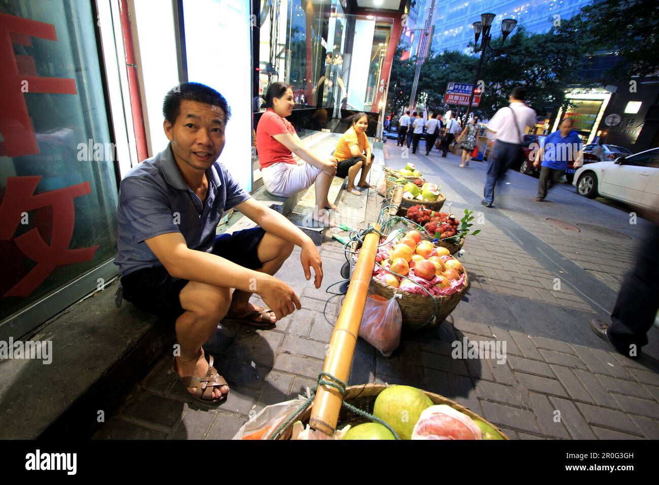 Smiling street hawker is sitting in front of his fruitbag in Chongqing ...