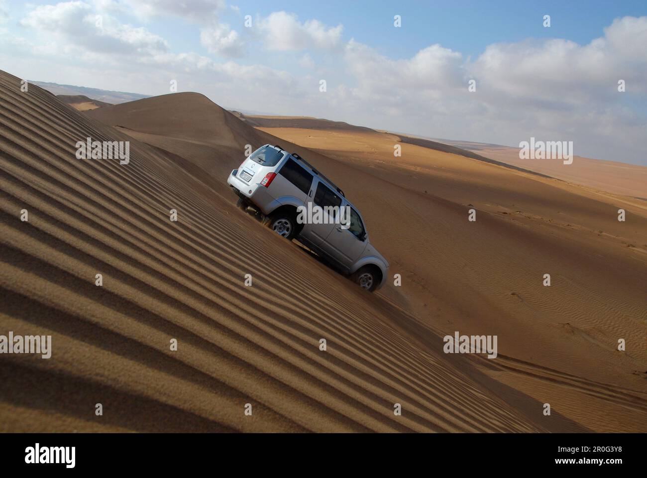 An all-terrain vehicle driving down a sand dune, Wahiba Sands, Oman ...