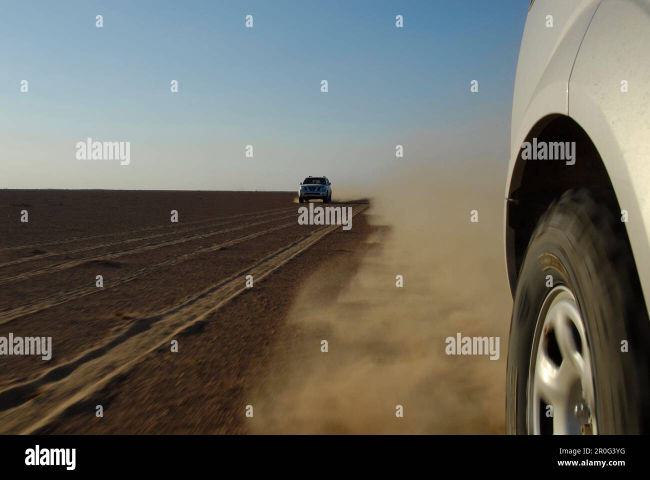 All-terrain vehicles driving on a sandy road under blue sky, Wahiba ...
