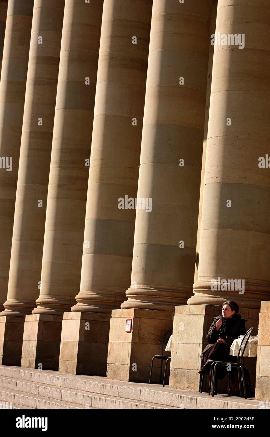 Woman sitting between the columns of the Koenigsbau in the sunlight ...