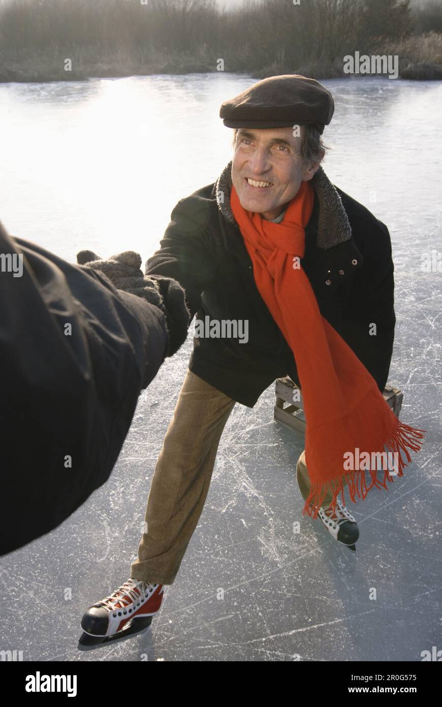 Person helping ice skater to stand up, Lake Ammersee, Upper Bavaria ...