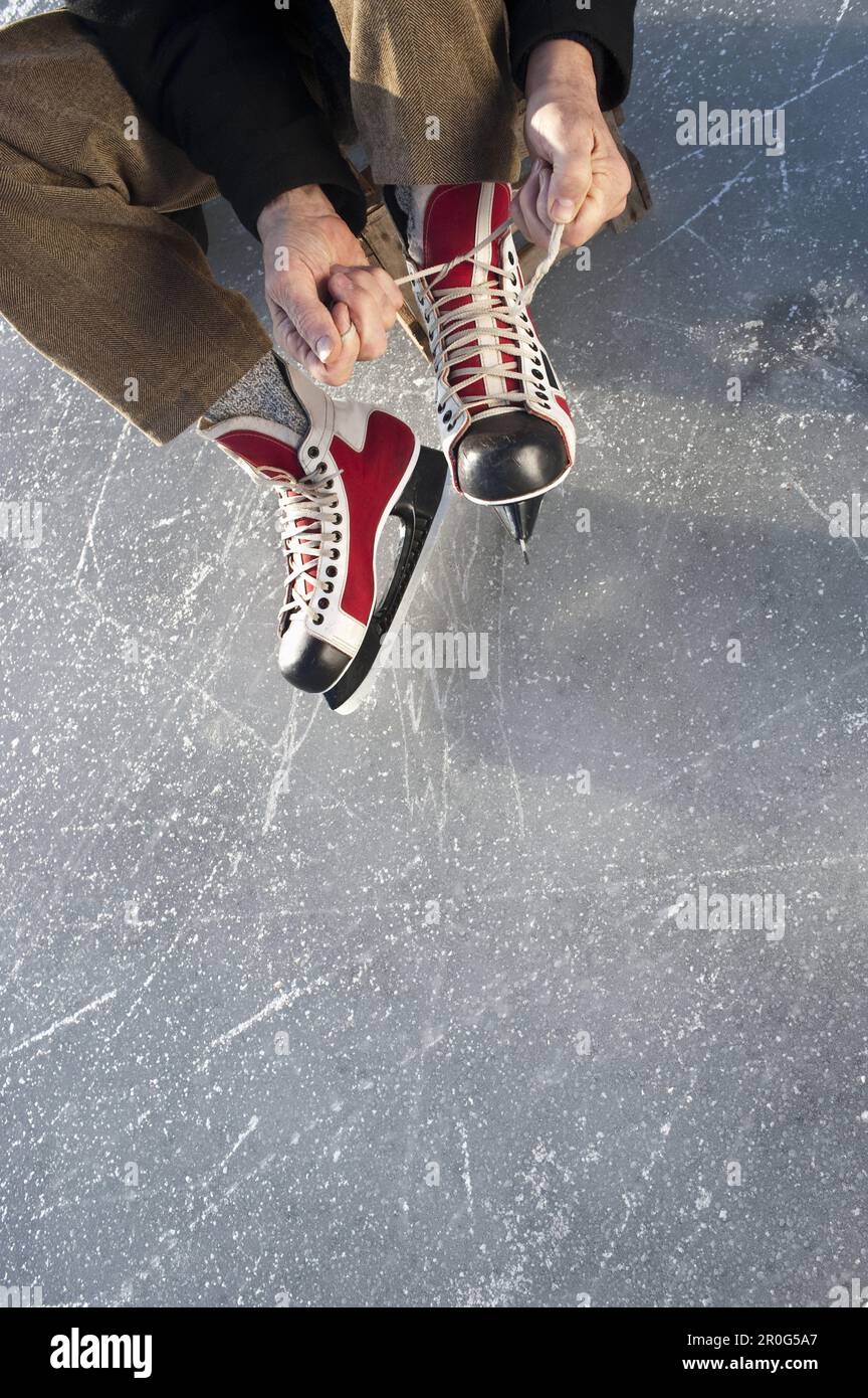 Senior man putting on ice skate, Lake Ammersee, Upper Bavaria, Germany ...