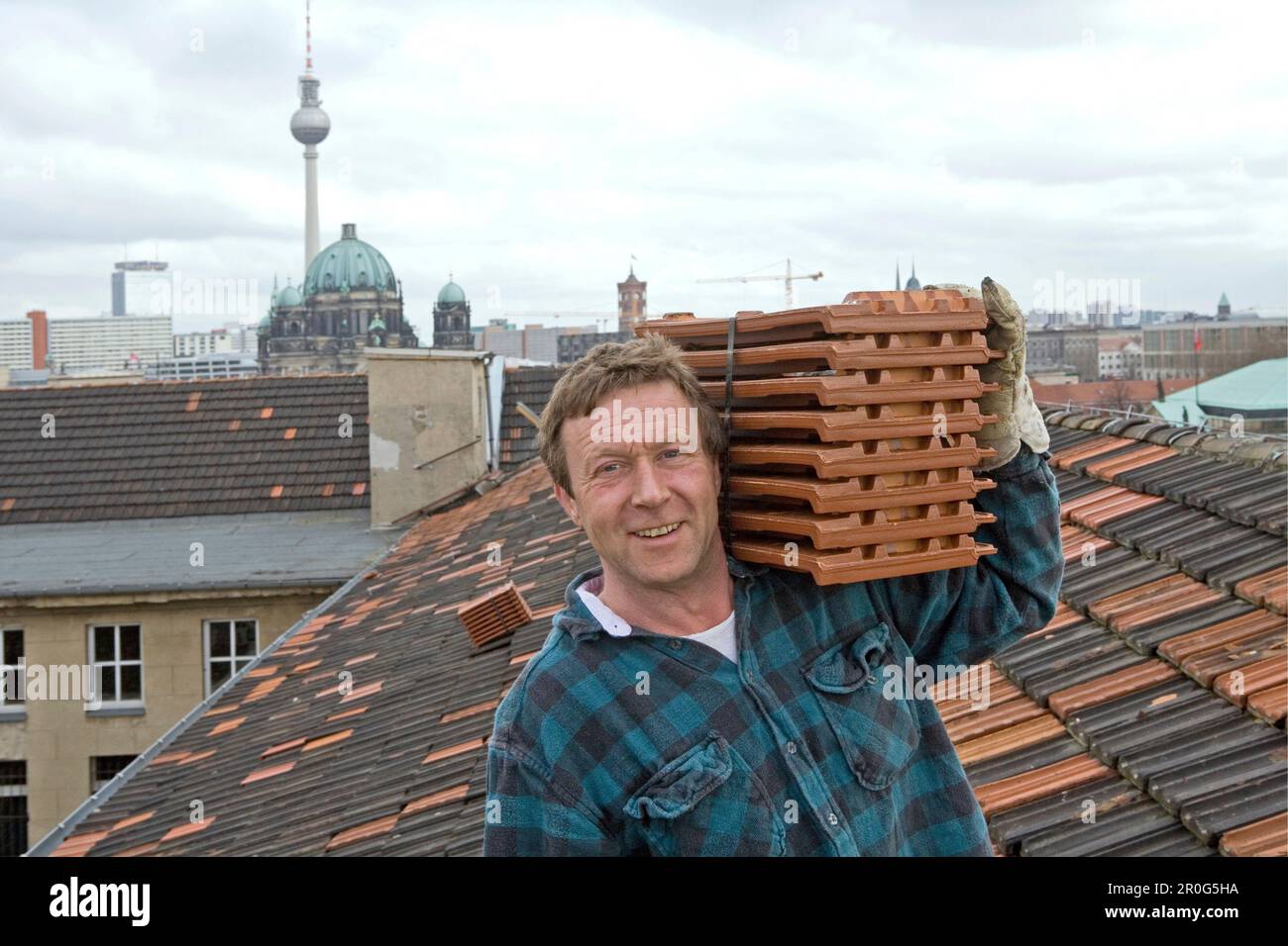 portrait, roof tiler carrying tiles on shoulder, on roof, Berlin ...