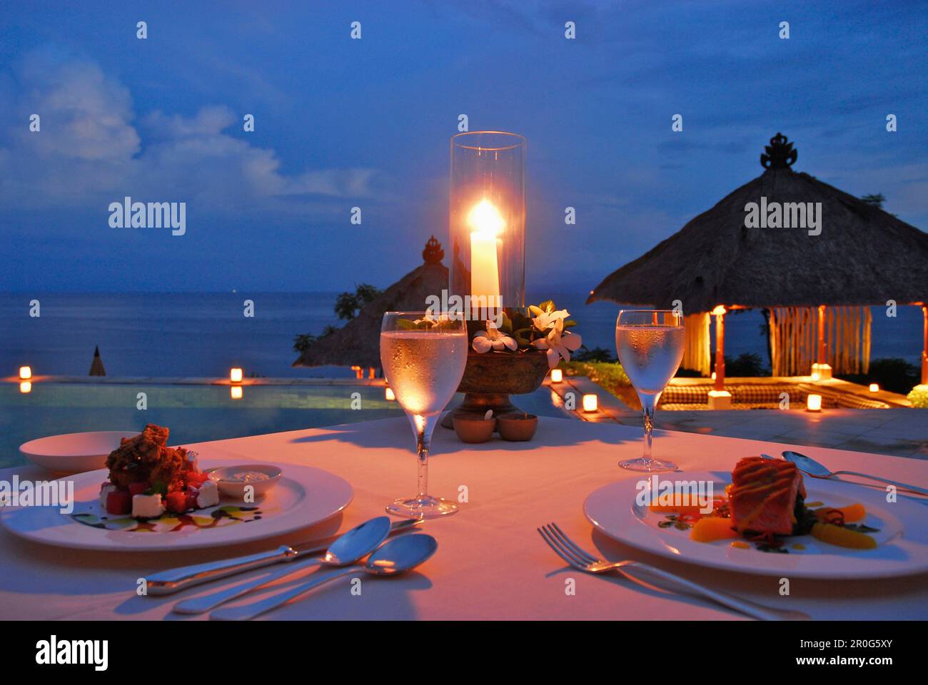 A table is laid at the pool at Amankila Resort in the evening, Candi ...
