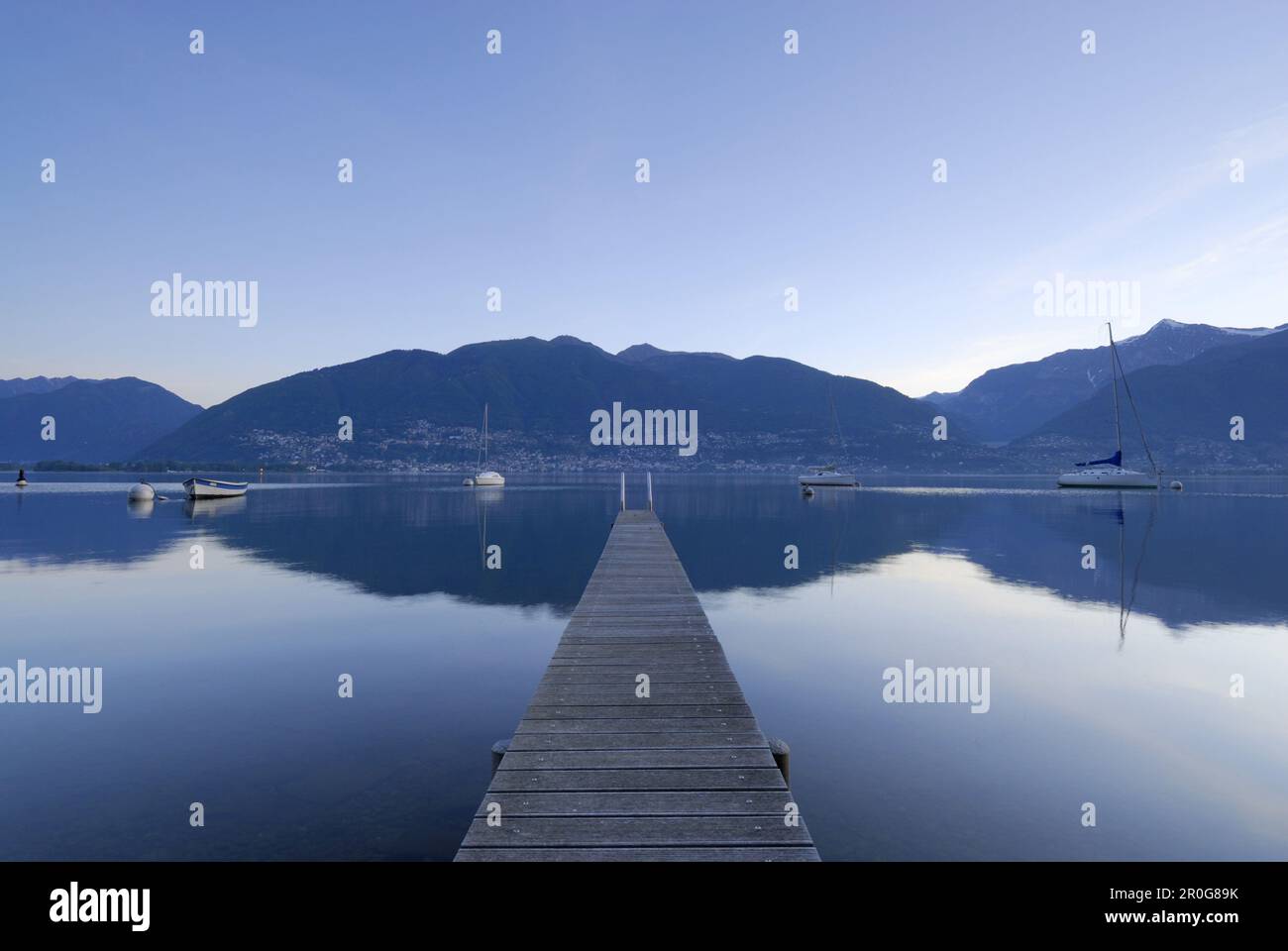 Wooden jetty leading into lake Maggiore with sailing boats, Locarno ...